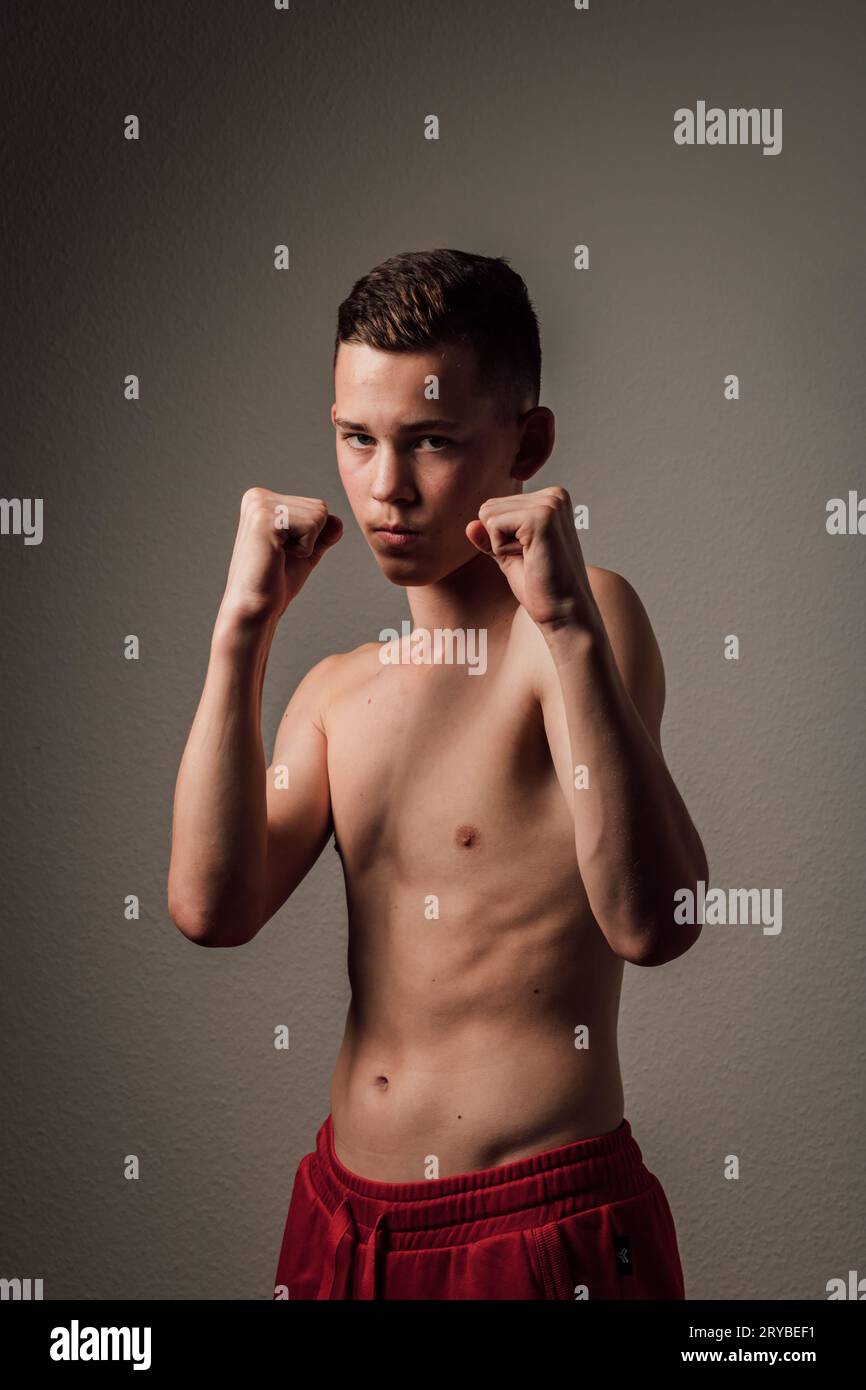A teenage boxer athlete is training to box on dark background ...