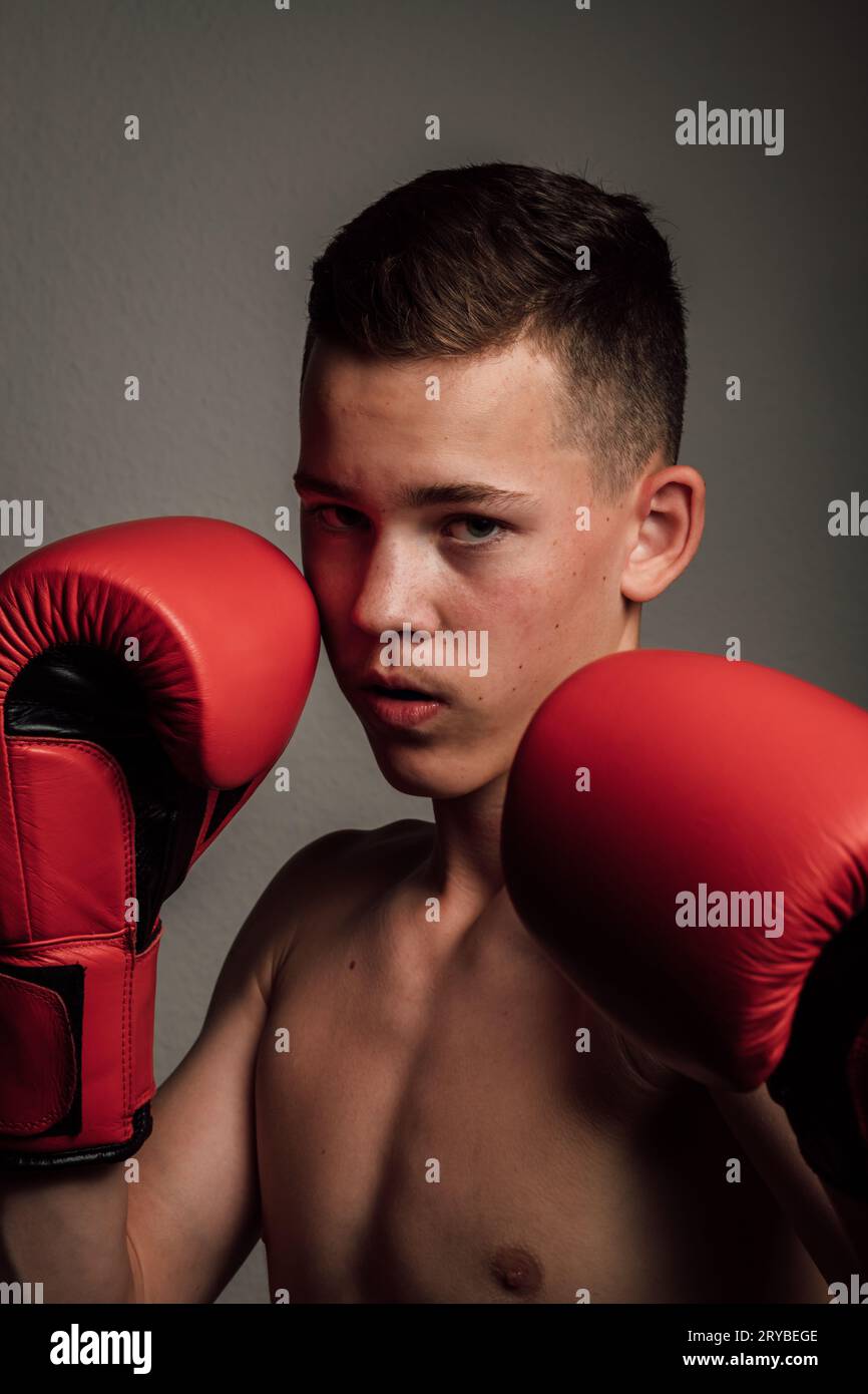 A teenage boxer athlete is training to box on dark background ...