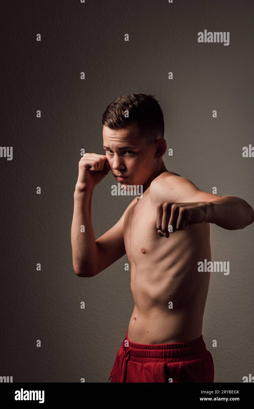 A teenage boxer athlete is training to box on dark background ...