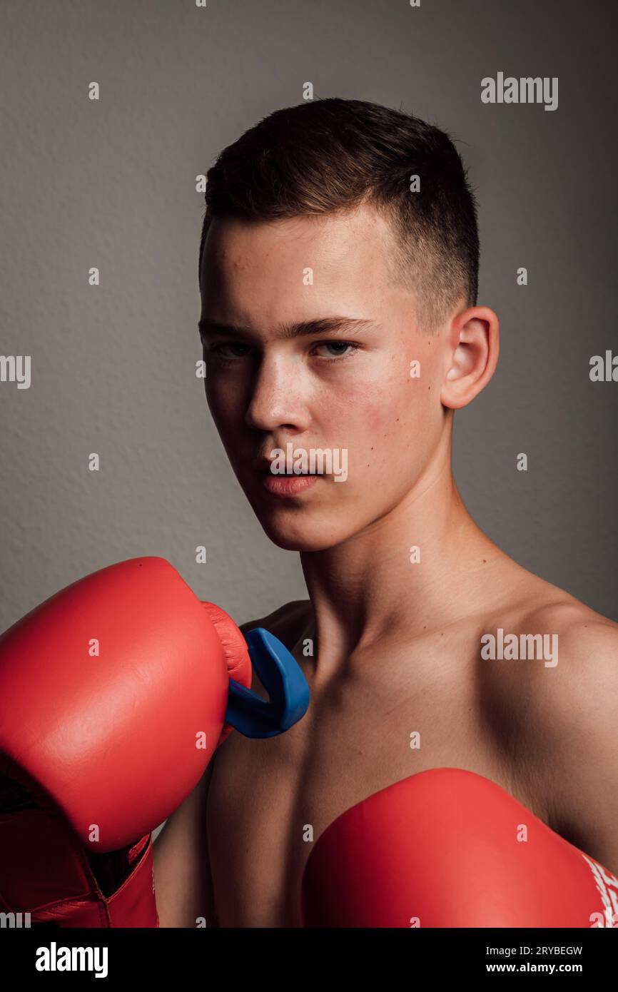 A teenage boxer athlete is training to box on dark background ...