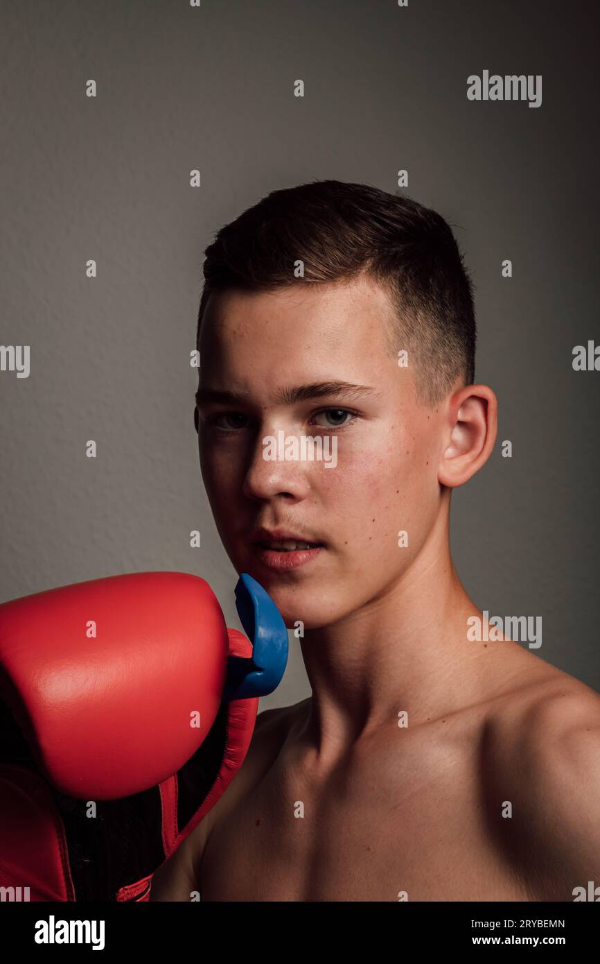 A teenage boxer athlete is training to box on dark background ...