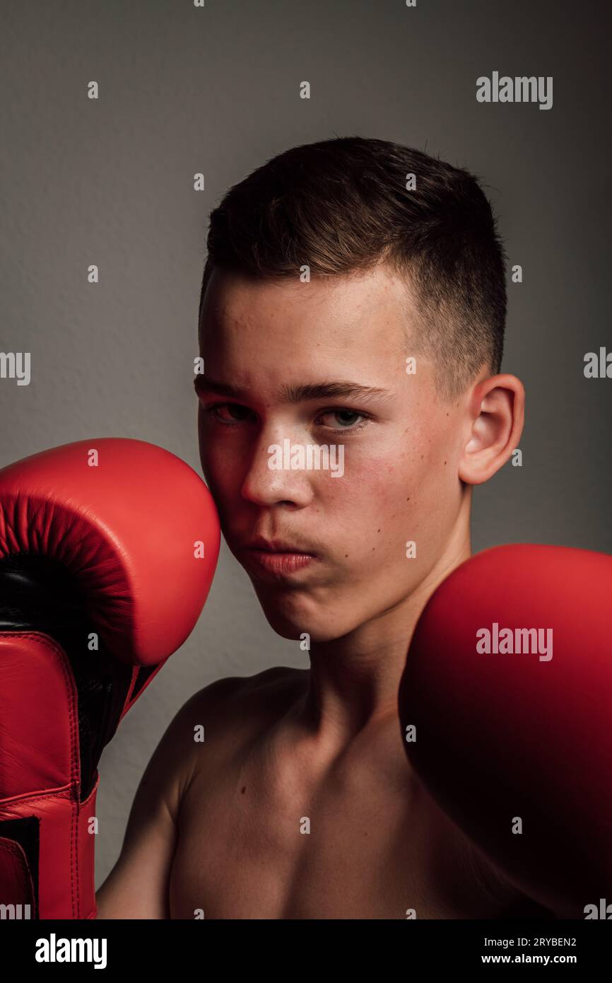 A teenage boxer athlete is training to box on dark background ...
