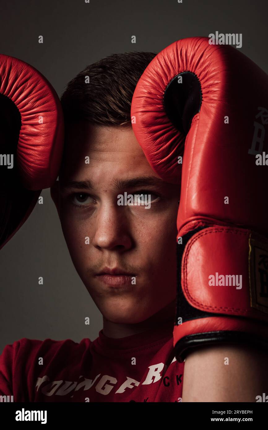 A teenage boxer athlete is training to box on dark background ...