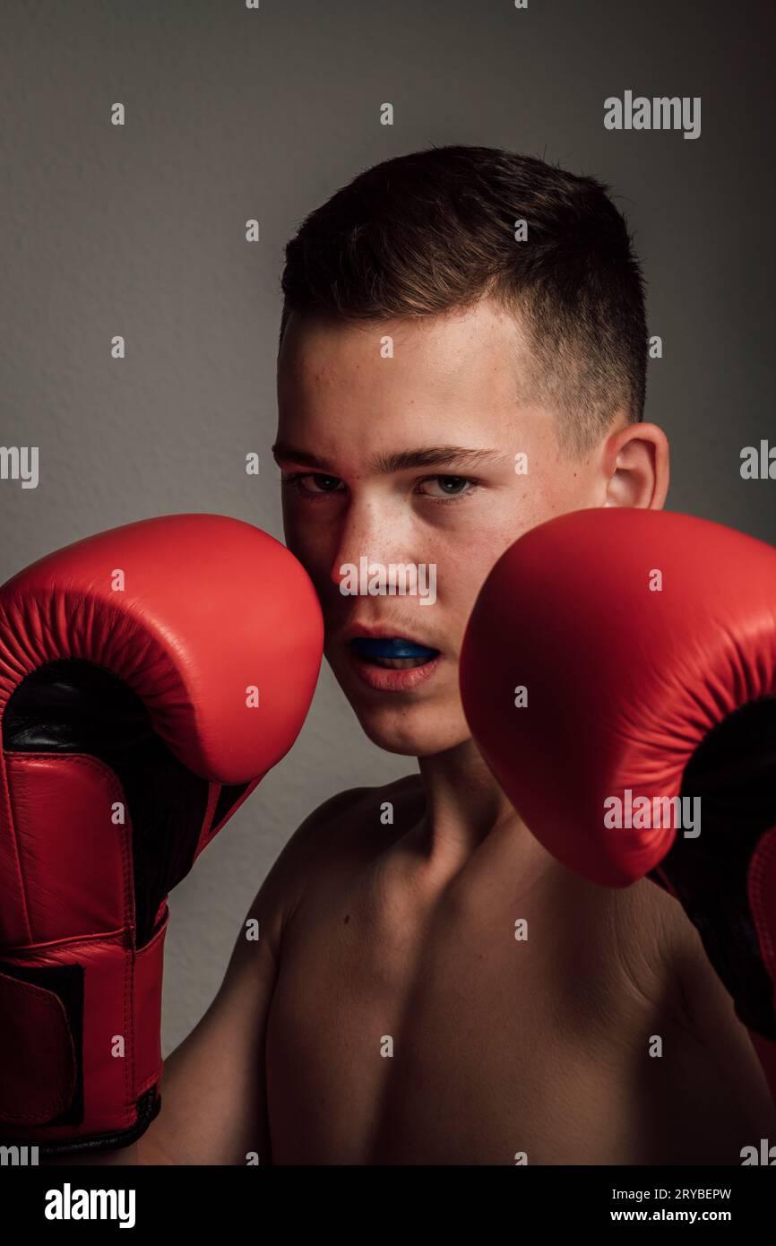 A teenage boxer athlete is training to box on dark background ...