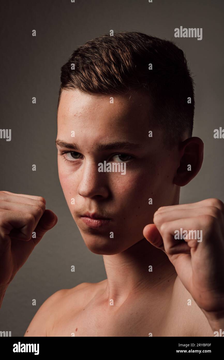 A teenage boxer athlete is training to box on dark background ...