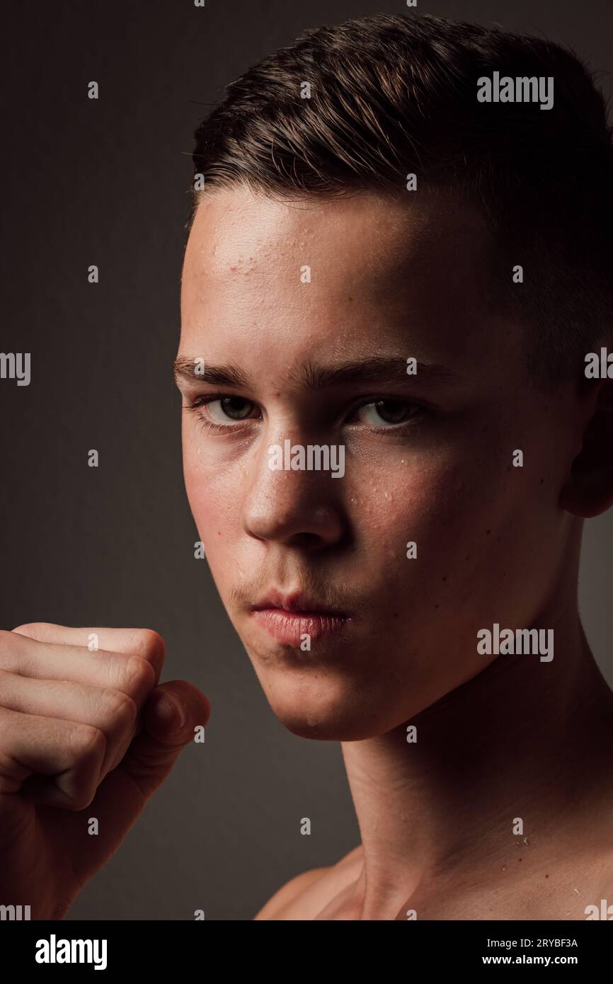 A teenage boxer athlete is training to box on dark background ...