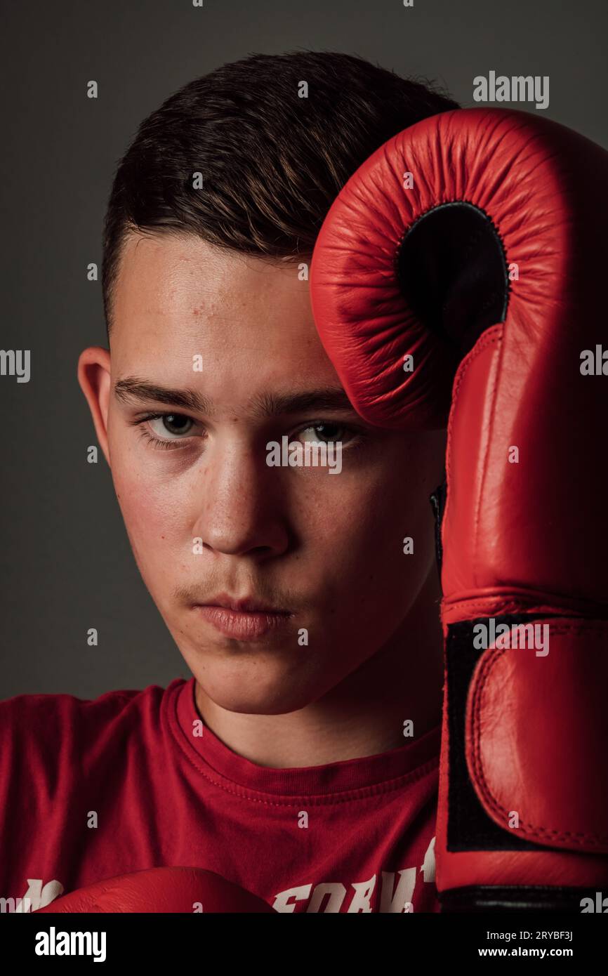 A teenage boxer athlete is training to box on dark background ...