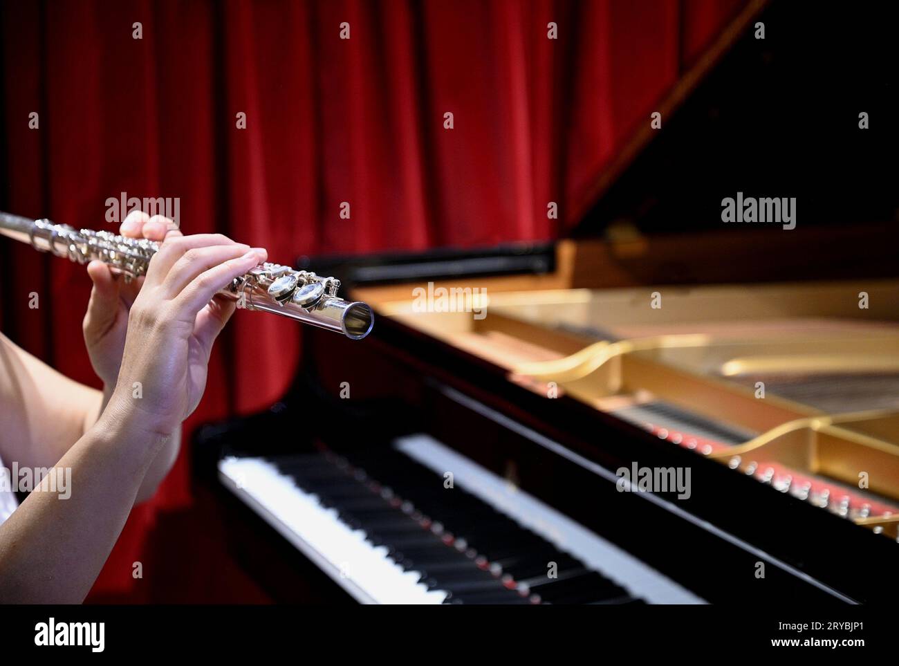 Young female flutist hands playing a western type concert flute with a ...