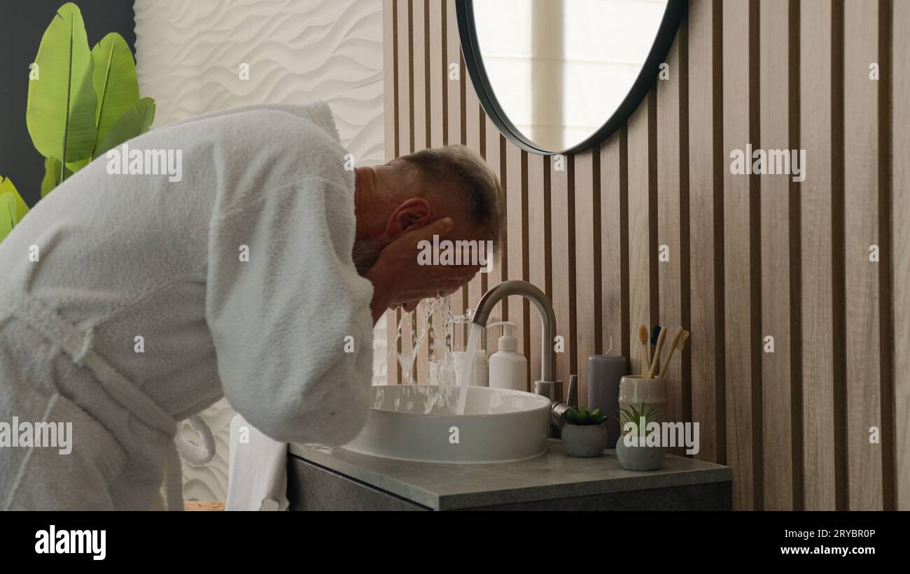Old Caucasian gray-haired man washing face with cold warm hot water ...