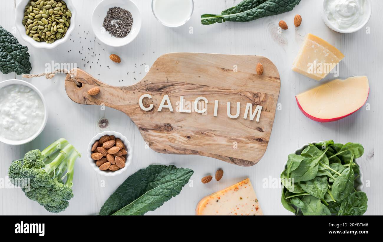 A variety of foods high in calcium surrounding a board with the word ...