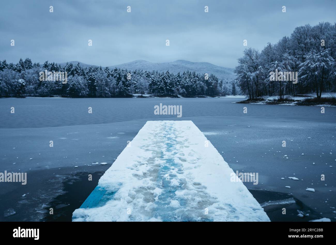 Dark landscape photo of mole (pier) covered of snow with frozen lake on ...