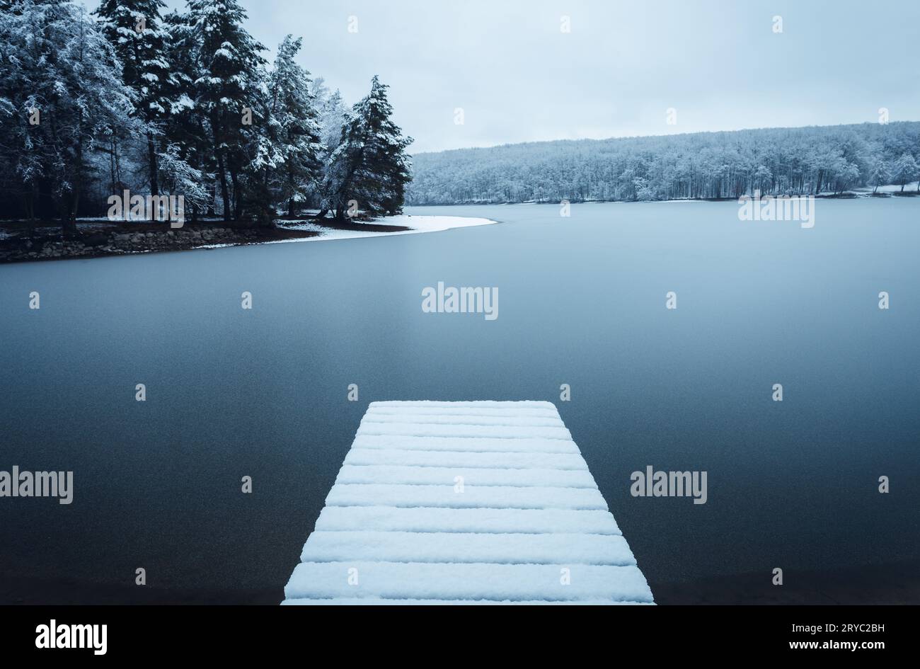 Dark landscape photo of mole (pier) covered of snow with frozen lake on ...