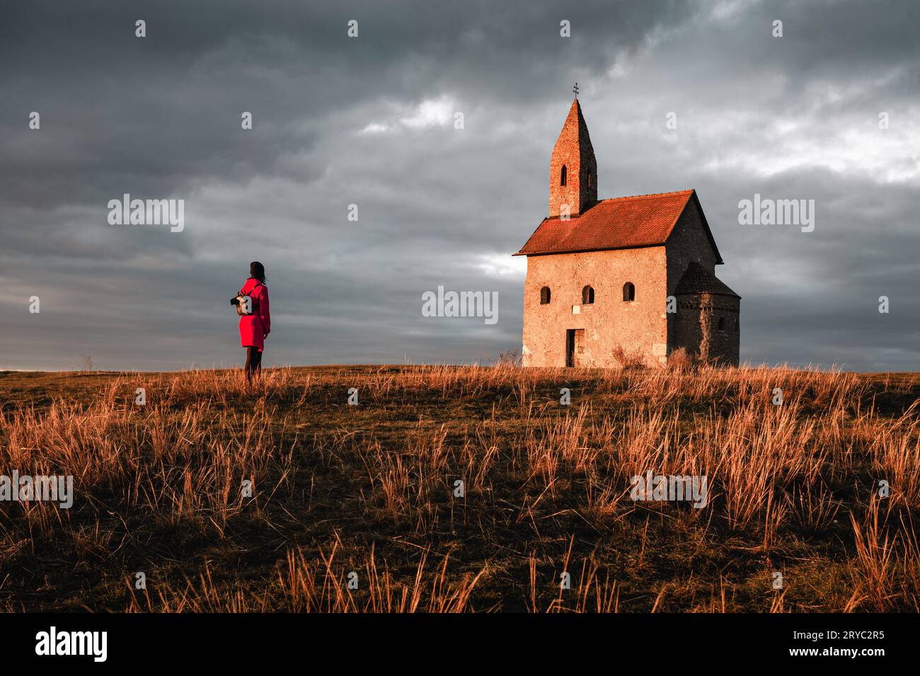 Woman tourist in red coat standing in front of Old Roman Catholic ...