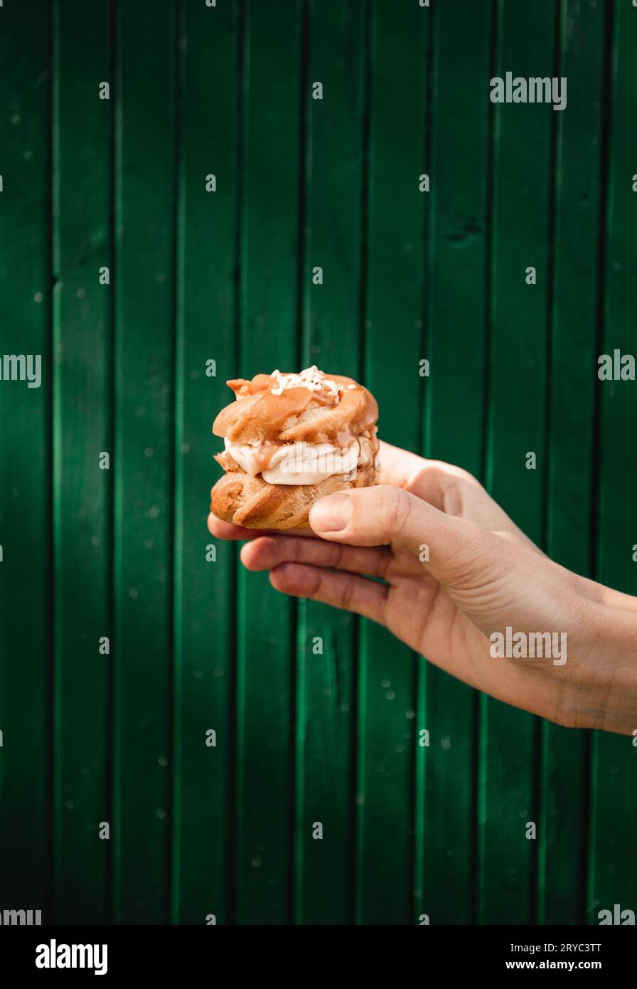 Female holding a cake in hand - green and dark background. Small tasty ...