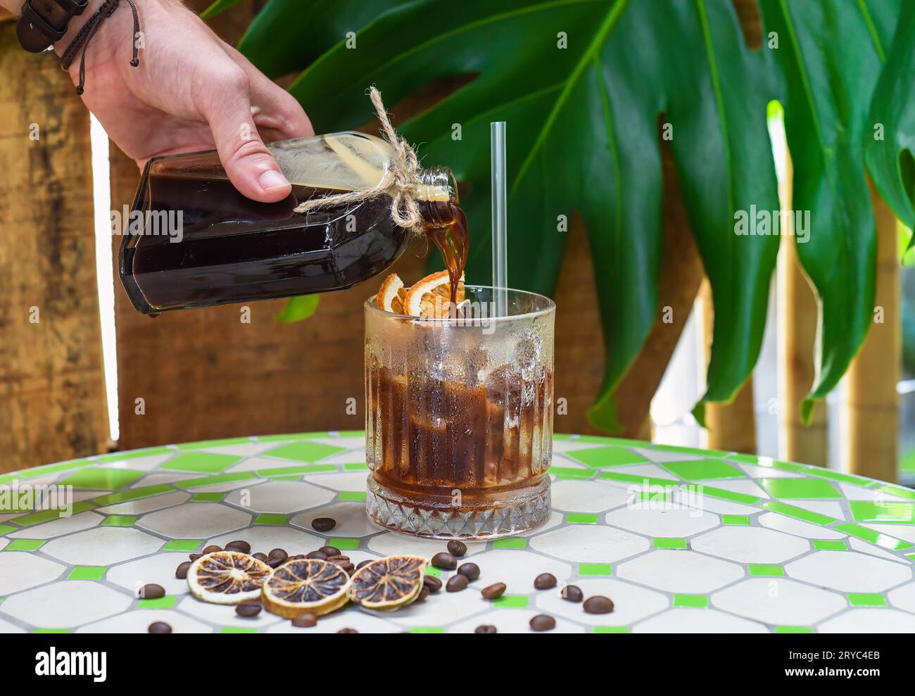Hand pouring cold brew coffee in a bottle with transparent glass full ...