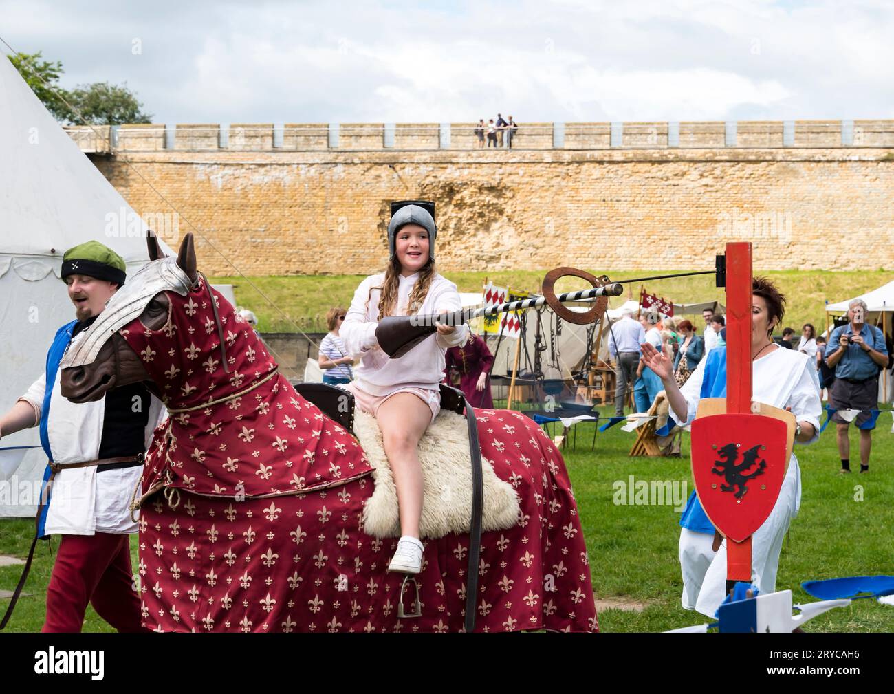 Young girl on practice jousting horse snags ring on lance at medieval jousting event, Lincoln ...