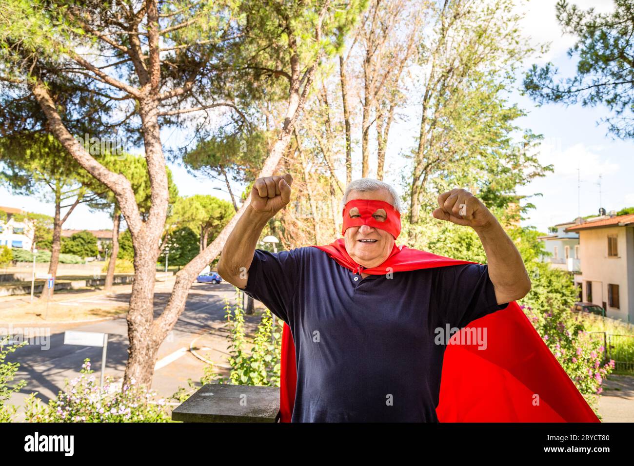Senior posing as superhero with red cloack and mask Stock Photo - Alamy