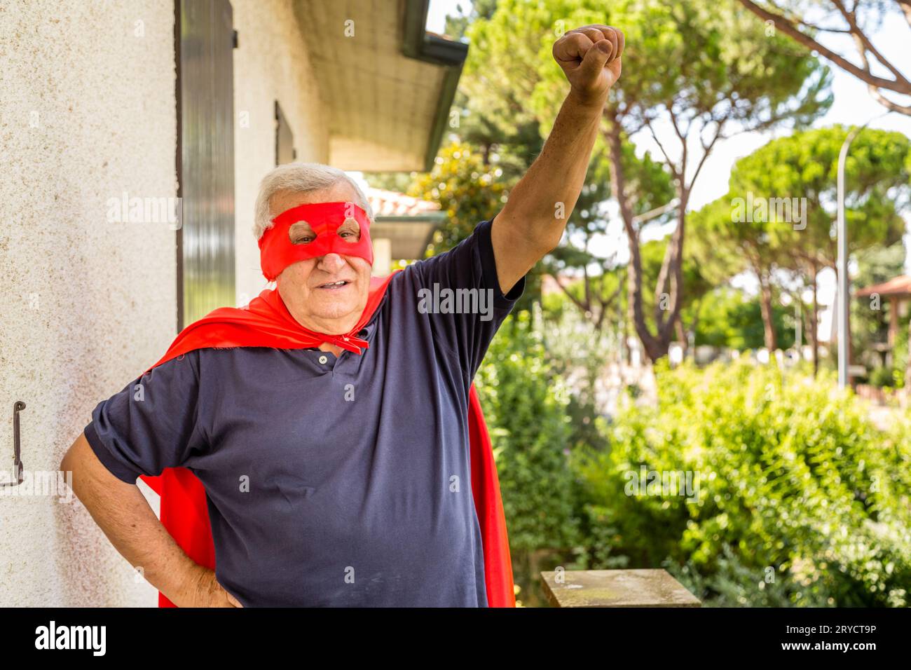Senior posing as superhero with red cloak and mask Stock Photo - Alamy