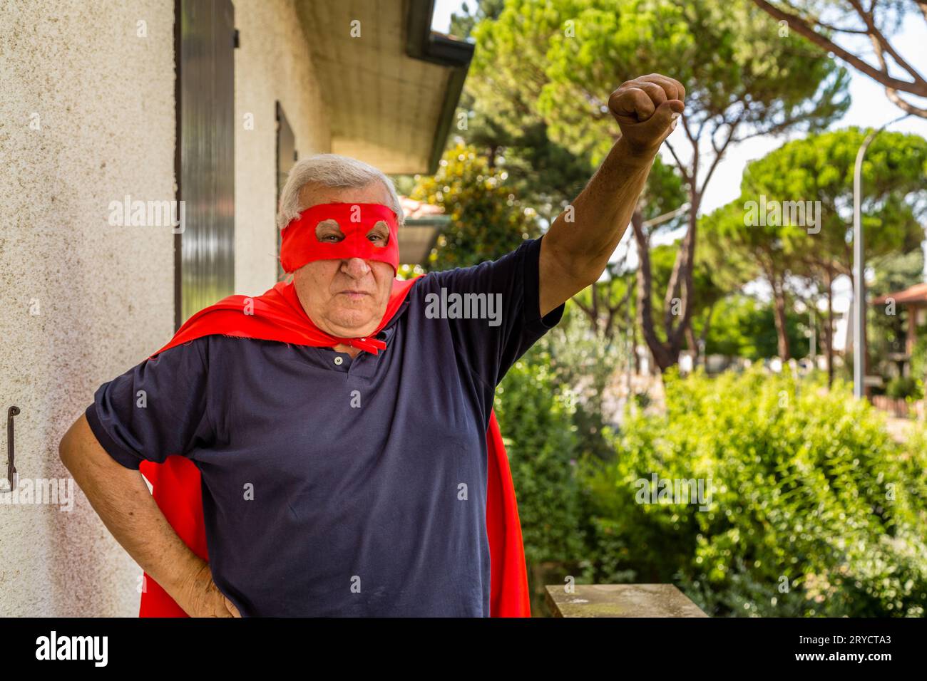 Senior posing as superhero with red cloak and mask Stock Photo - Alamy