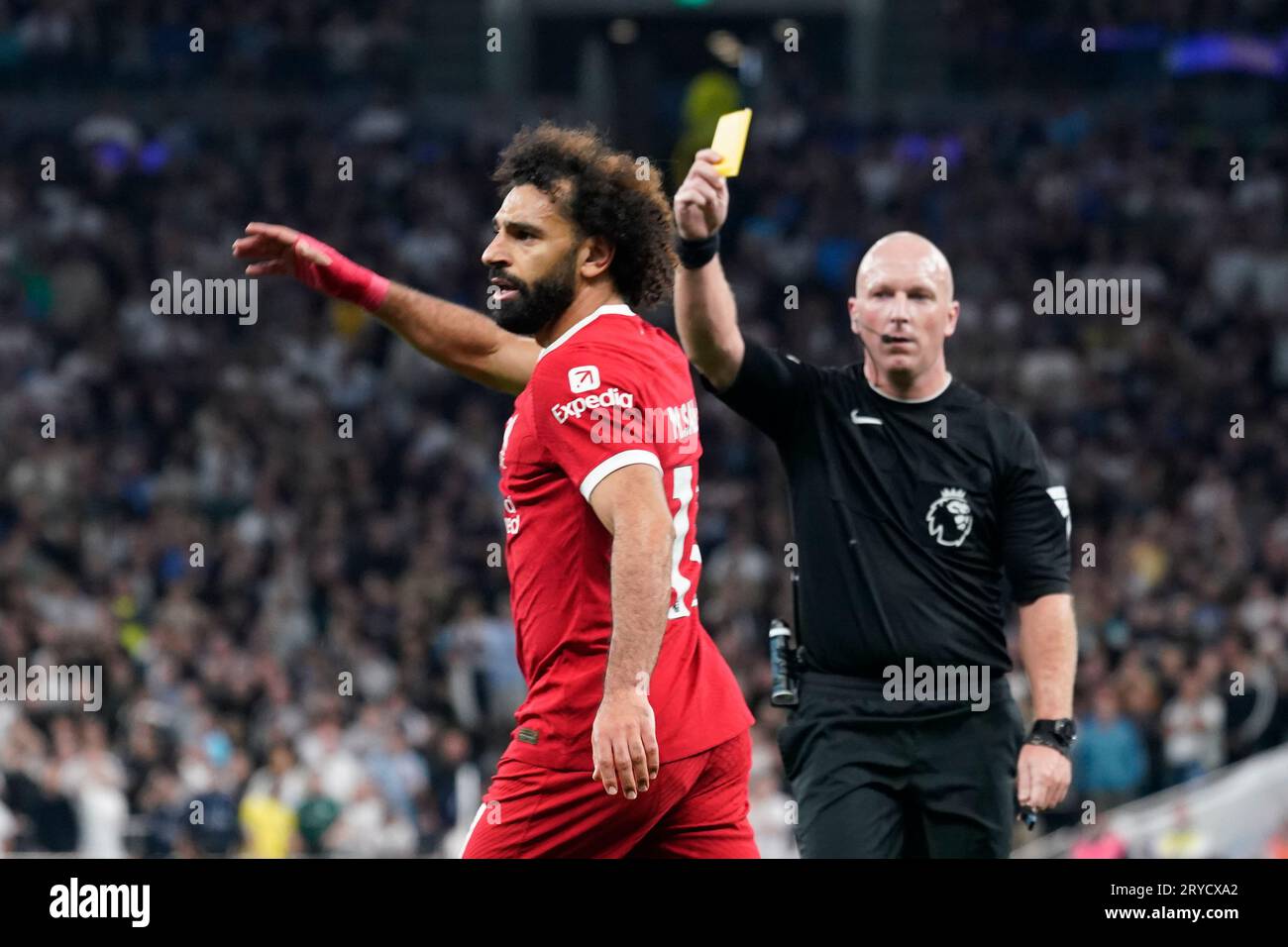 Referee Simon Hooper shows the yellow card to Liverpool's Mohamed Salah ...