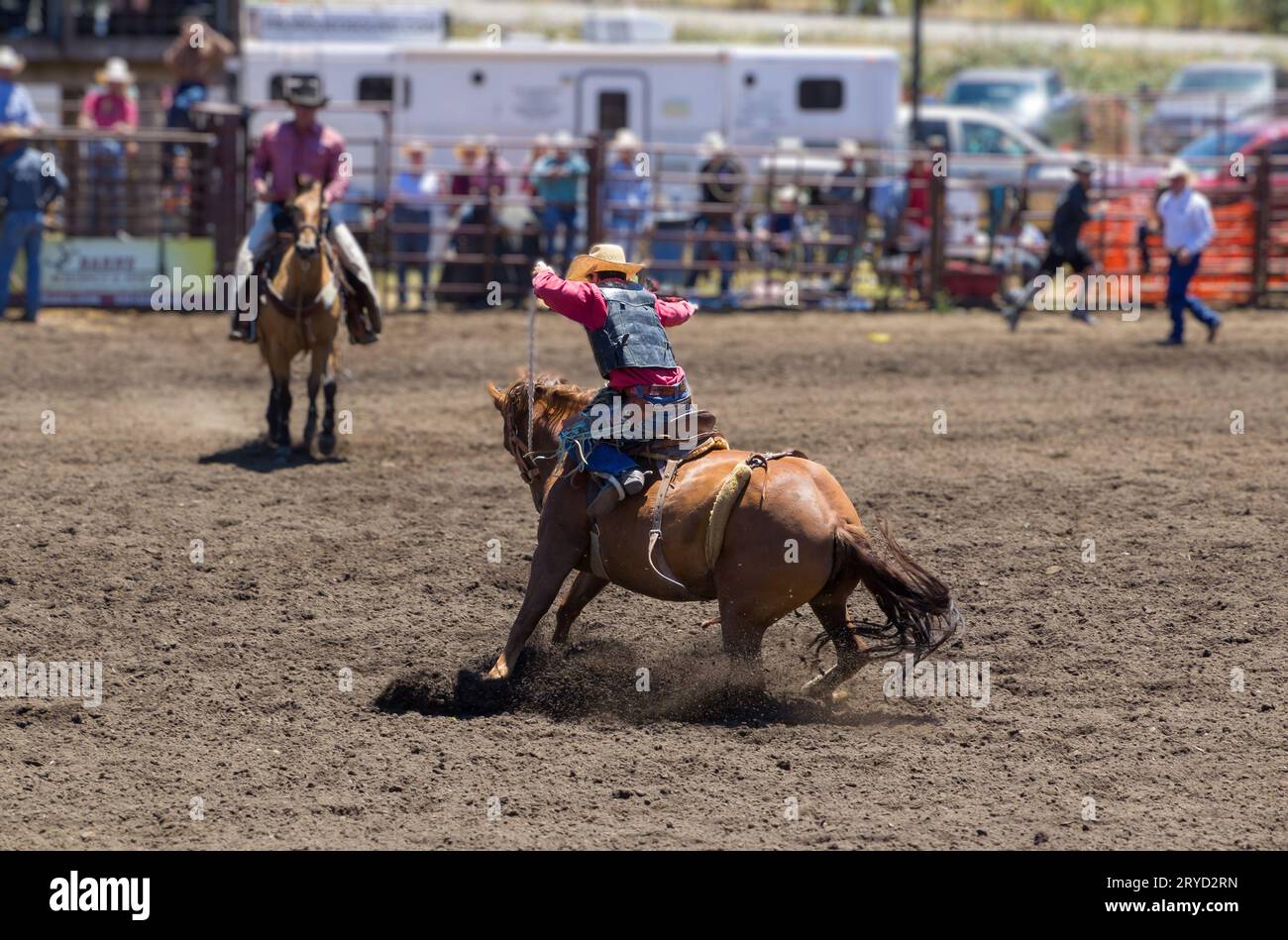 A cowboy is riding a bucking bronco at a rodeo. An out of focus rider ...
