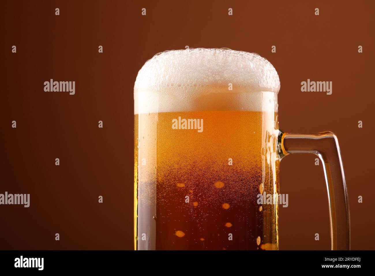 Close up pouring frothy beer in glass over brown Stock Photo - Alamy
