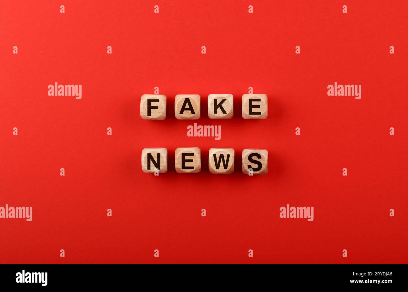 Wooden cubes with FAKE NEWS words over red Stock Photo - Alamy