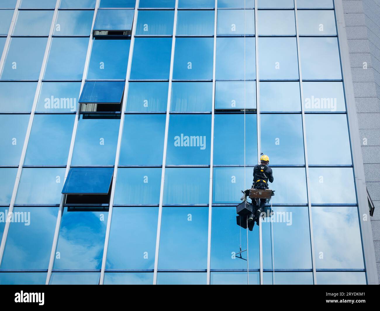 Window cleaner working on a glass facade suspended Stock Photo - Alamy