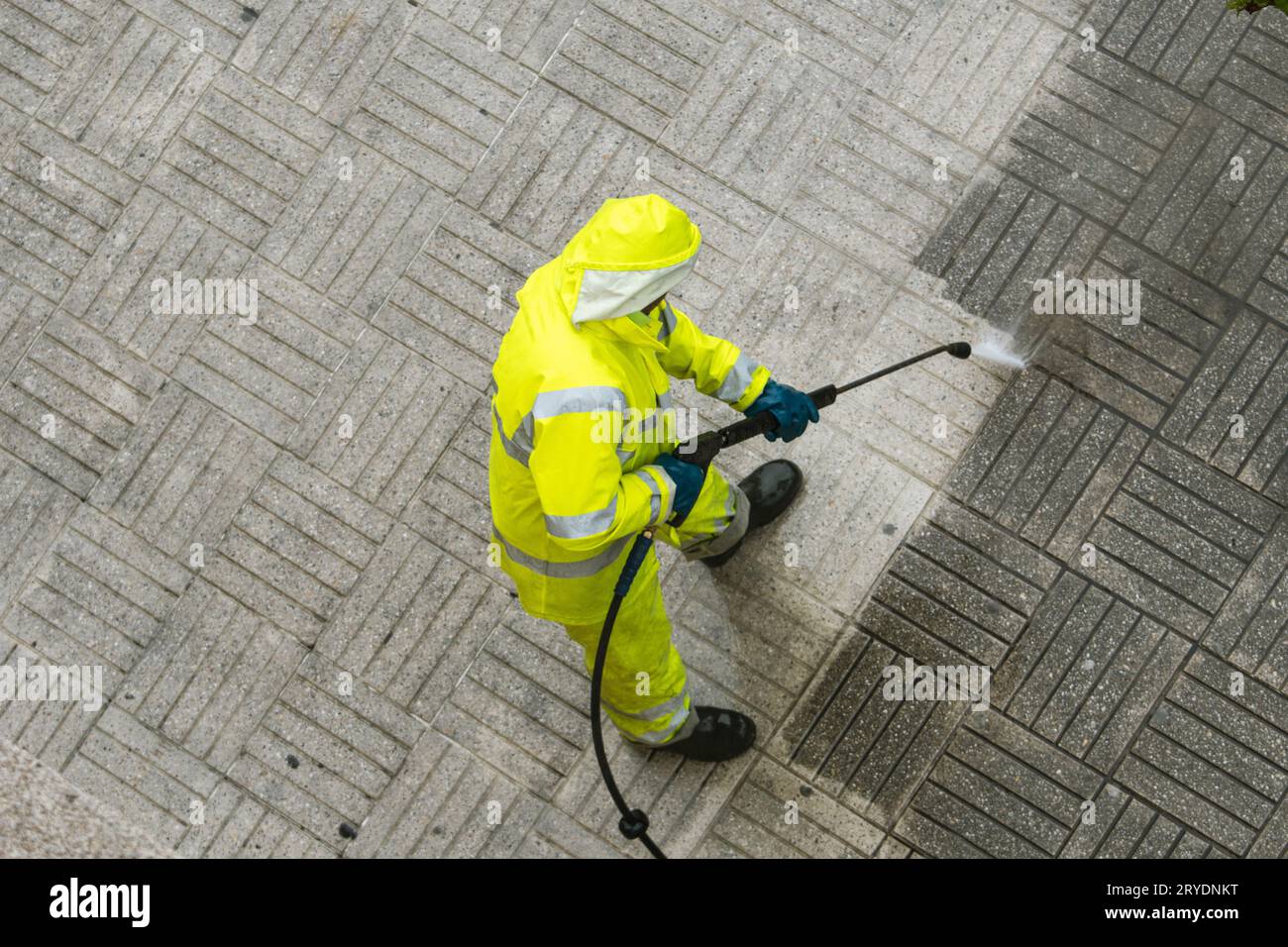 Top view of a Worker cleaning the street sidewalk with high pressure ...