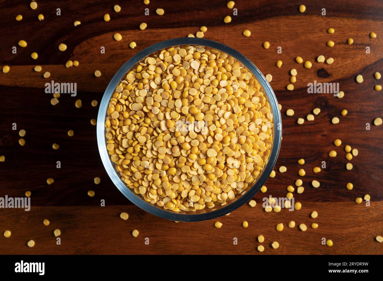 A glass bowl of yellow toor daal- pigeon peas scattered around on ...