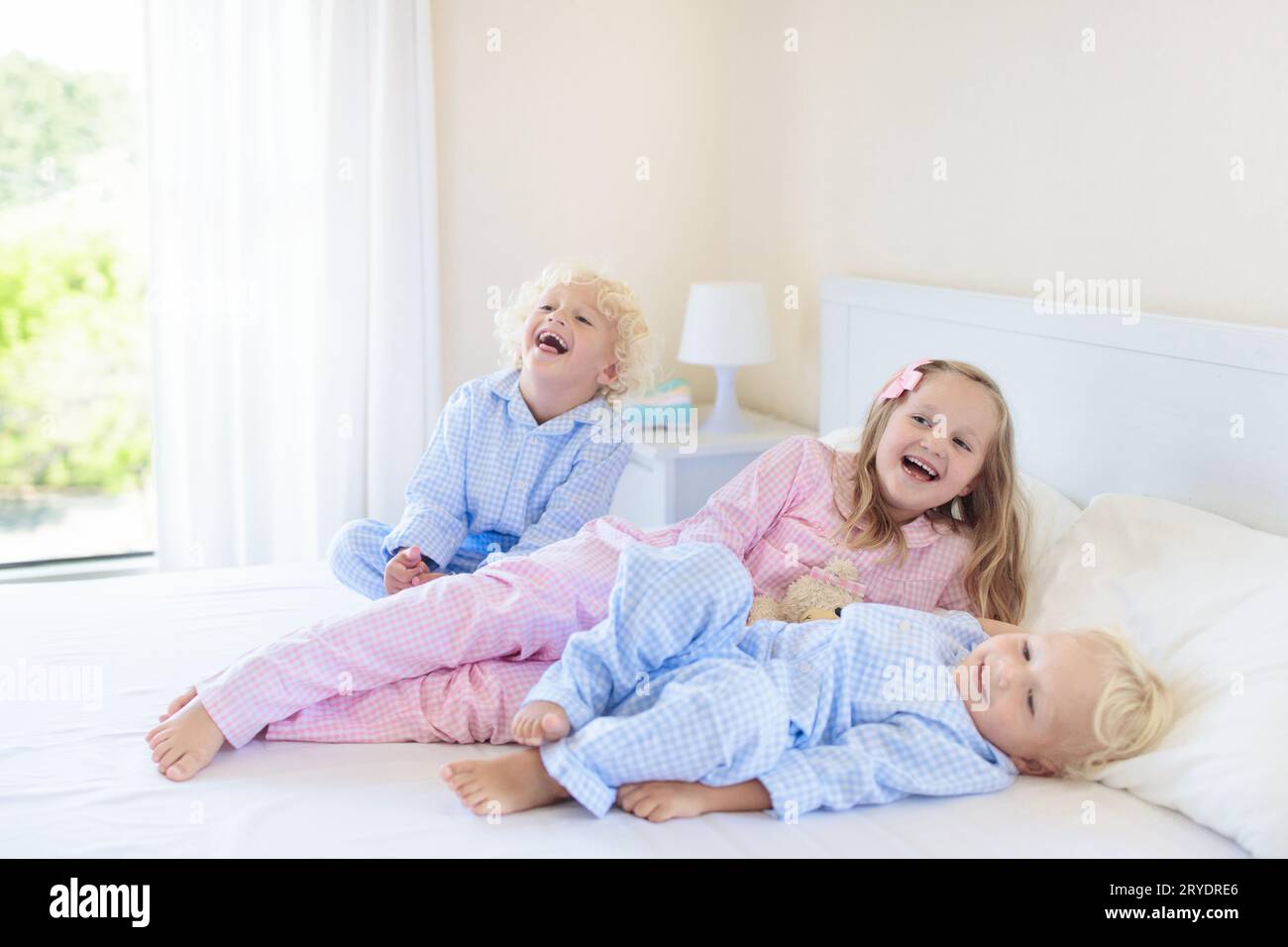 Kids playing in parents bed. Children wake up in sunny white bedroom ...