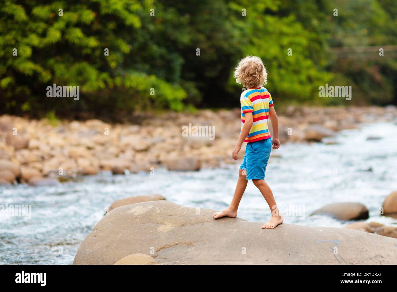 Children hiking in Alps mountains crossing river. Kids play in water at ...
