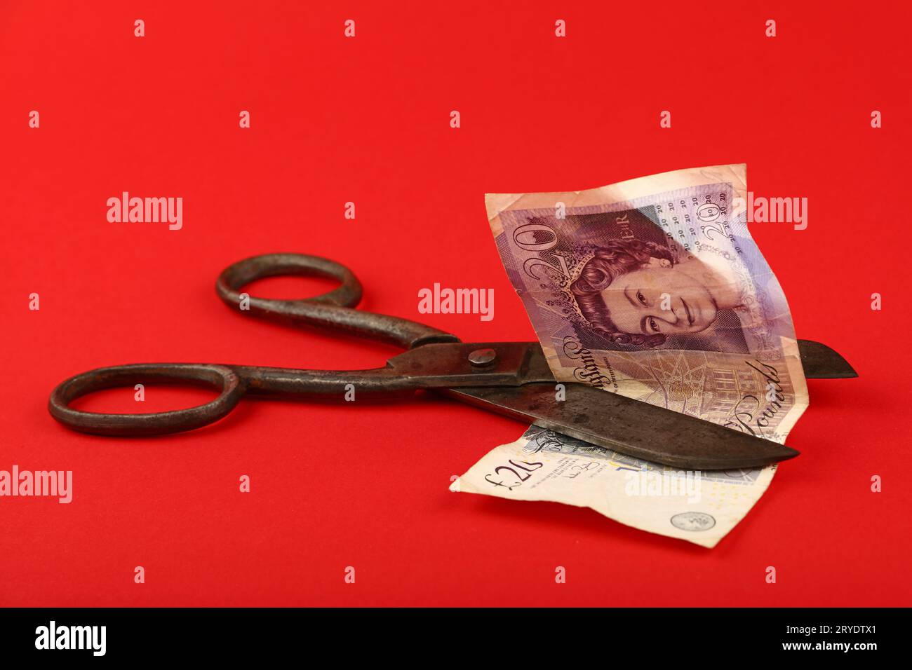 Scissors cut British Pound over red background Stock Photo - Alamy