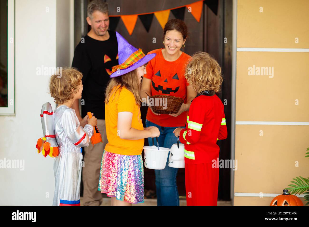 Kids trick or treat on Halloween night. Dressed up children at decorated house door. Boy and ...