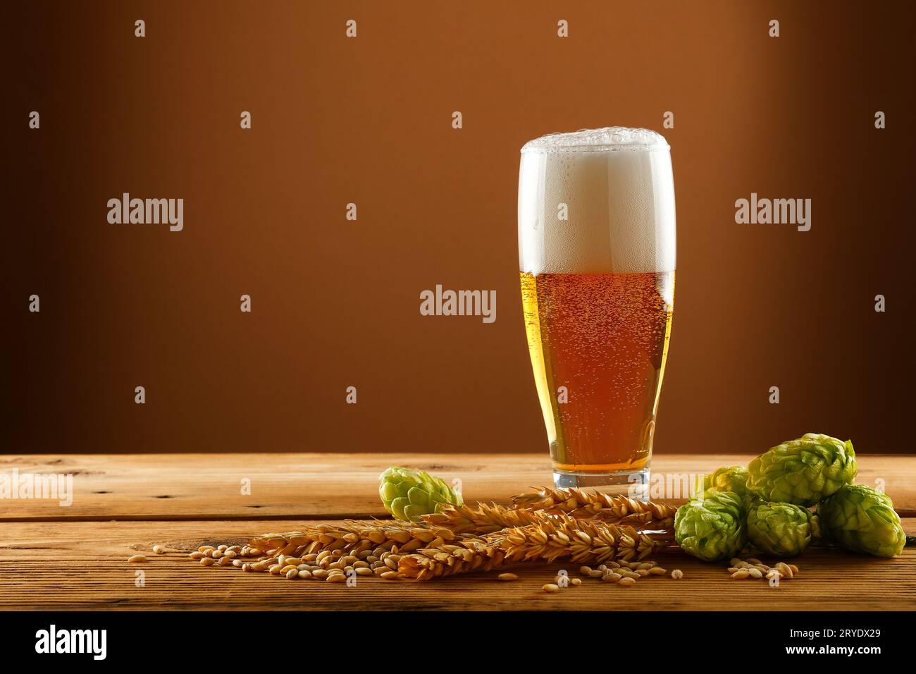 Close up beer glass, hops and barley over brown Stock Photo - Alamy