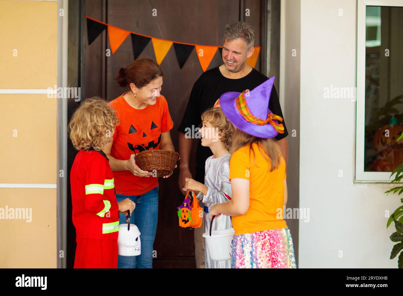 Kids trick or treat on Halloween night. Dressed up children at ...