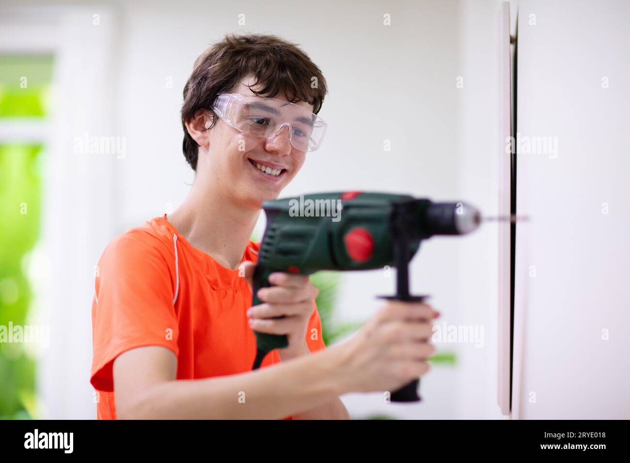 Young man drilling a hall in a wall. Home renovation. Contractor ...