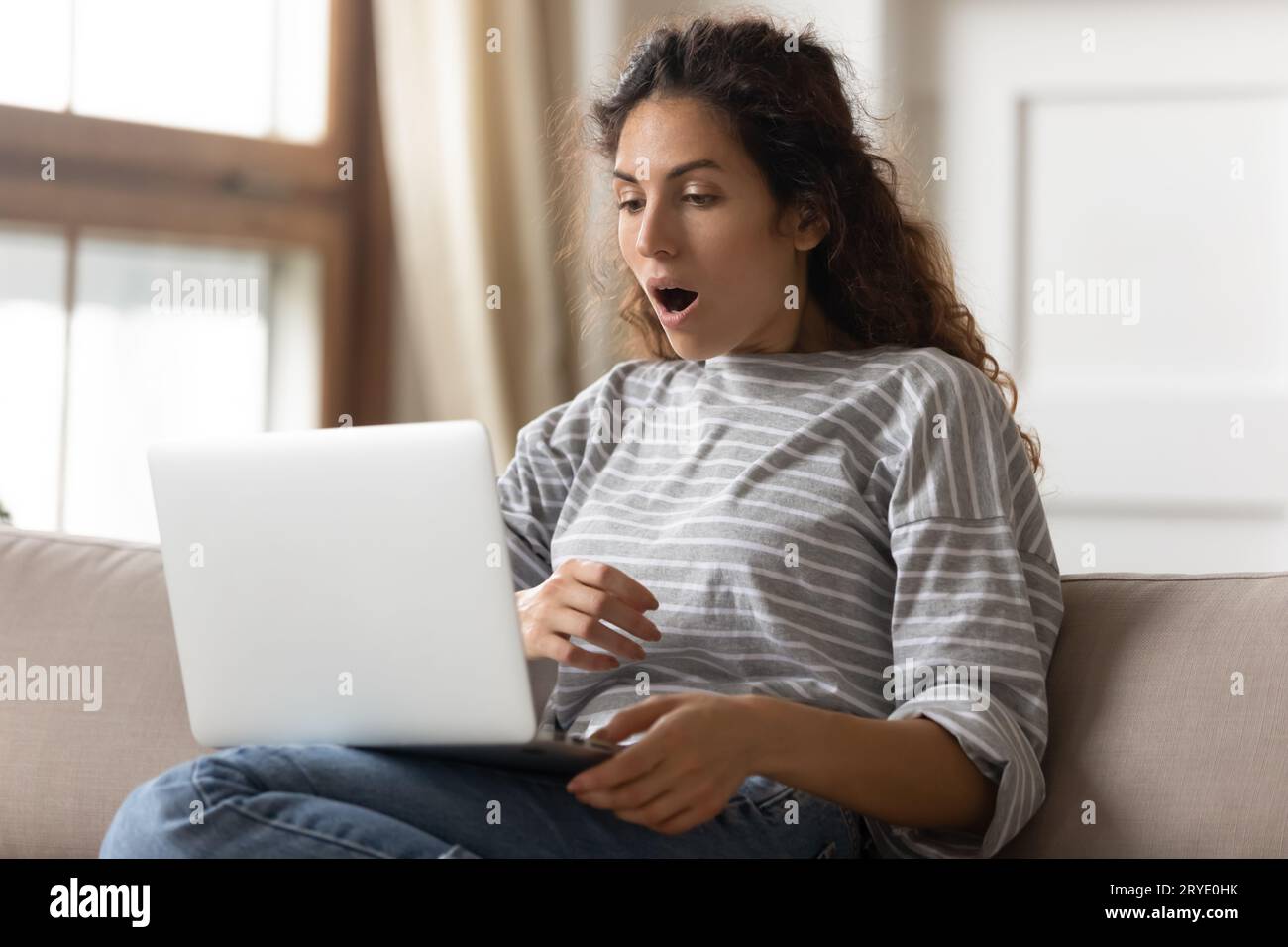 Millennial girl shocked reading news on laptop Stock Photo - Alamy