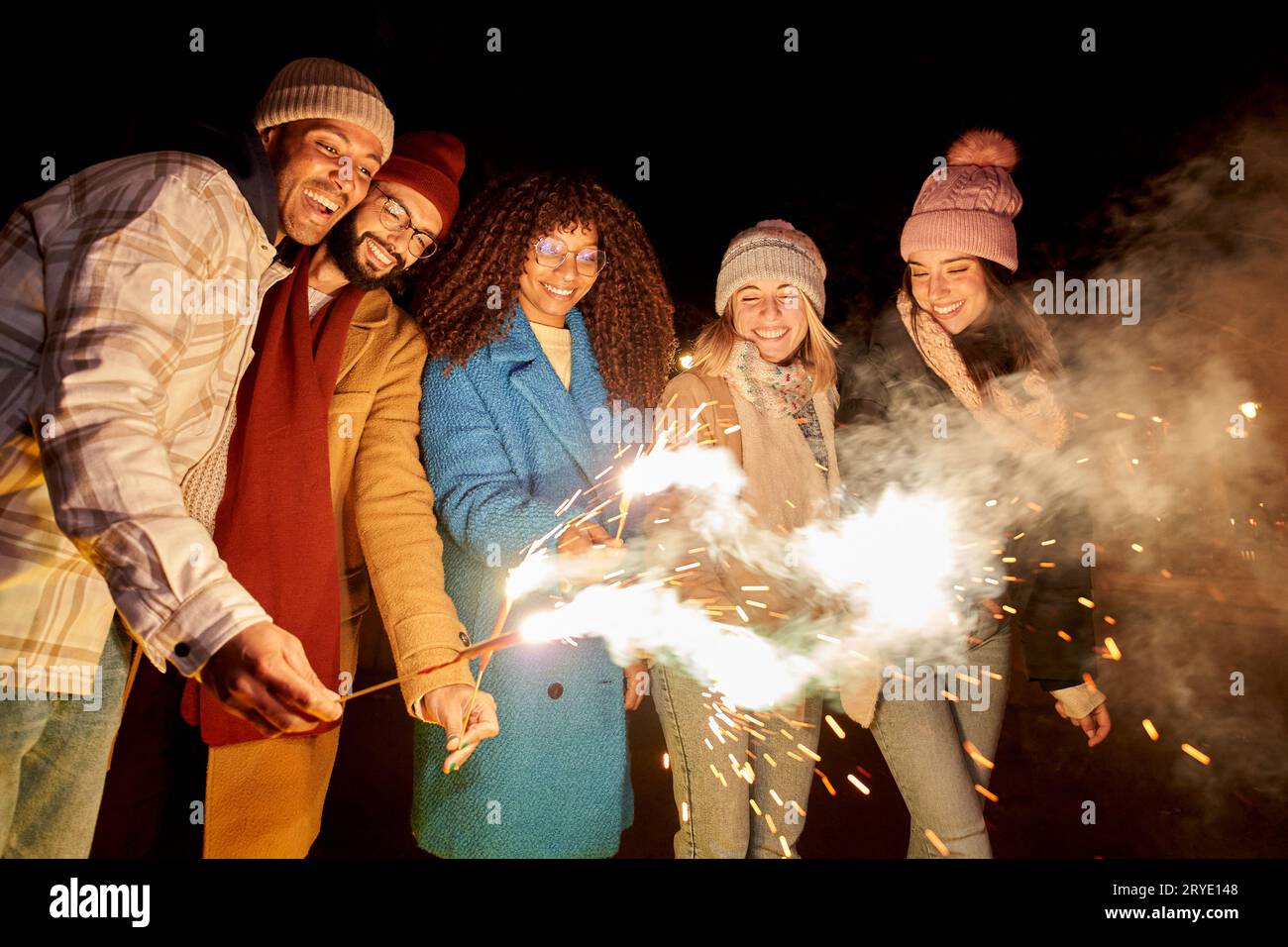 Group of happy people having fireworks party at winter night ...