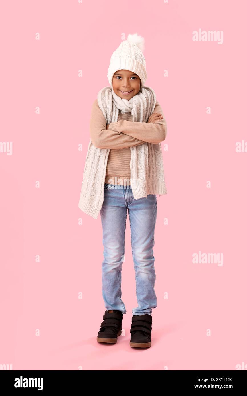 Freezing African-American boy in winter clothes on pink background ...