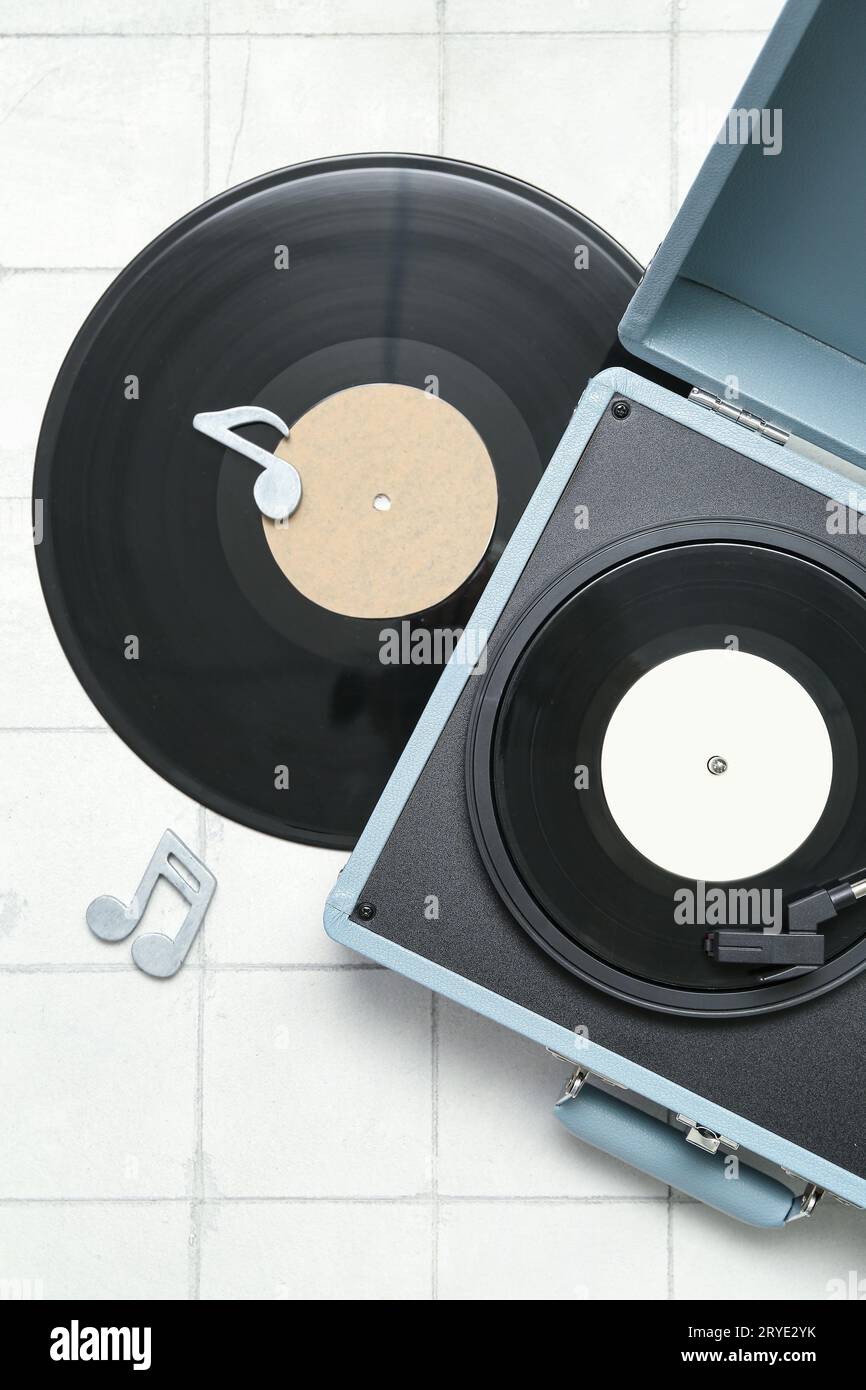Record player with vinyl disks and note signs on white tile background ...