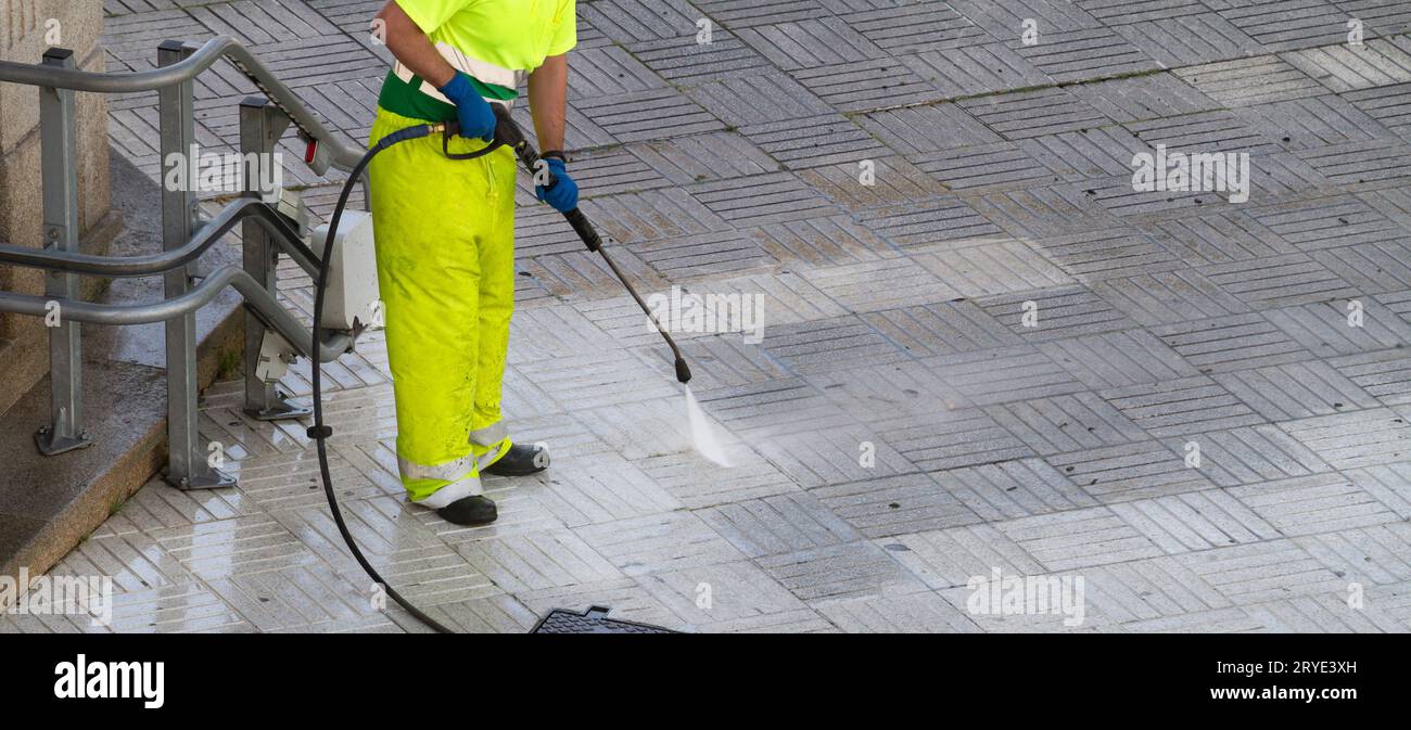 Worker cleaning a street sidewalk with high pressure water jet Stock ...