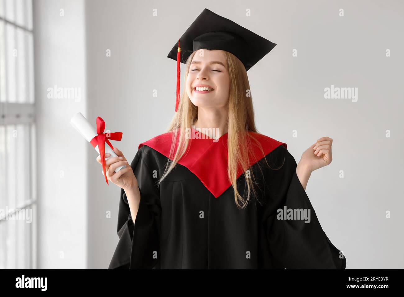Female graduate student with diploma near window in room Stock Photo ...