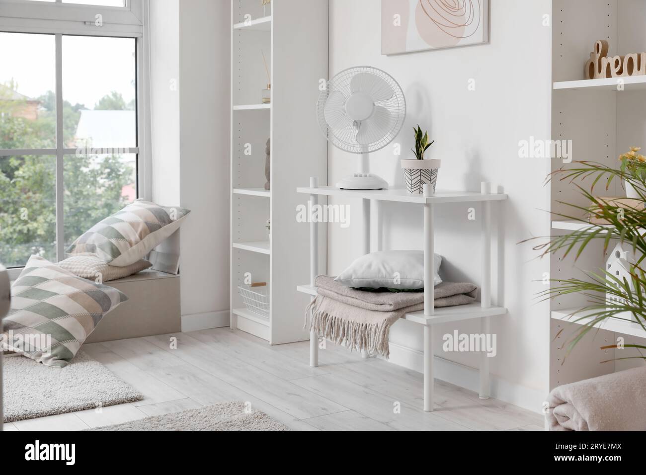 Interior of light living room with electric fan on shelf Stock Photo ...