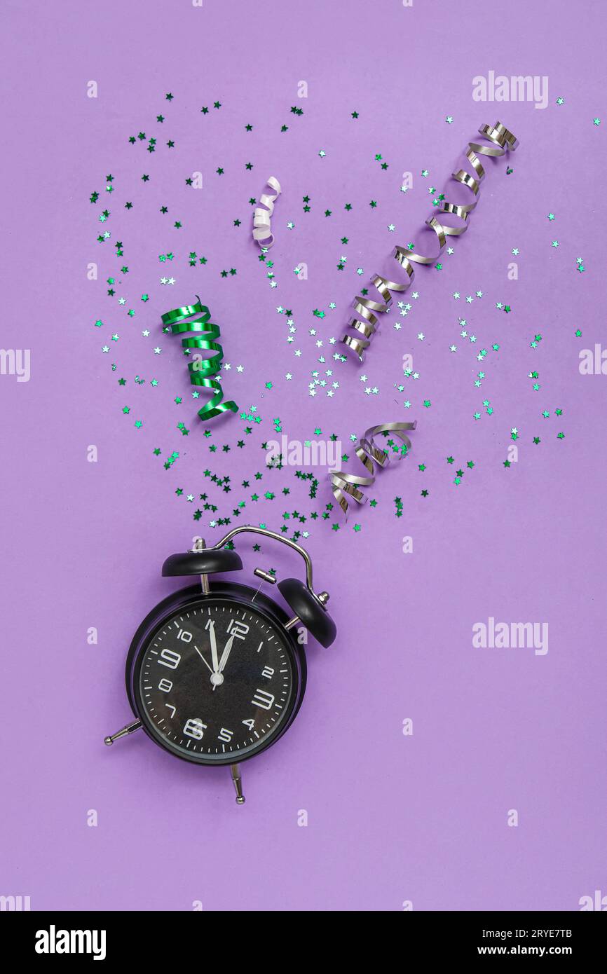 Alarm clock and confetti on lilac background Stock Photo - Alamy
