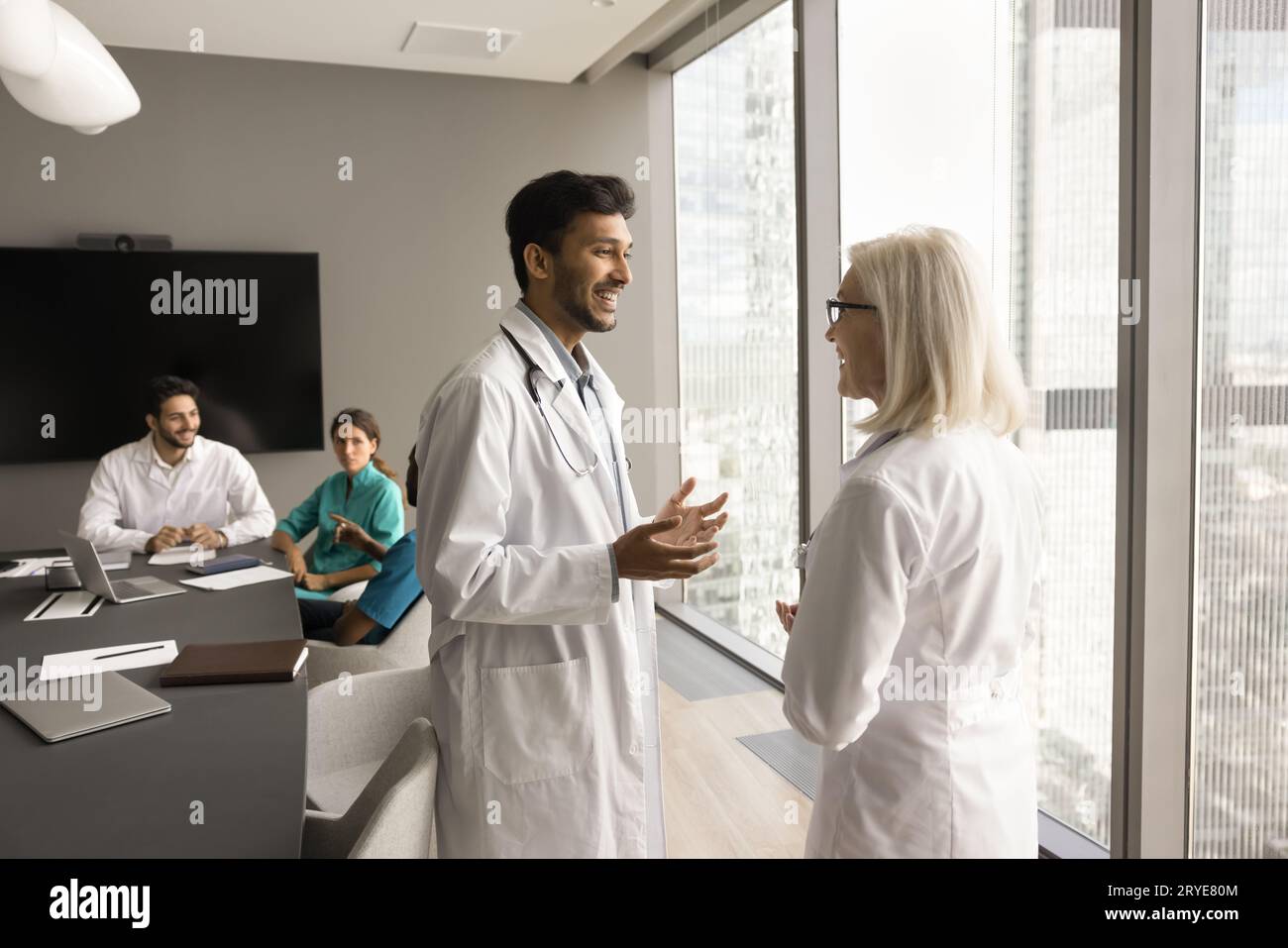 Positive doctor man and elder colleague talking in meeting room Stock ...