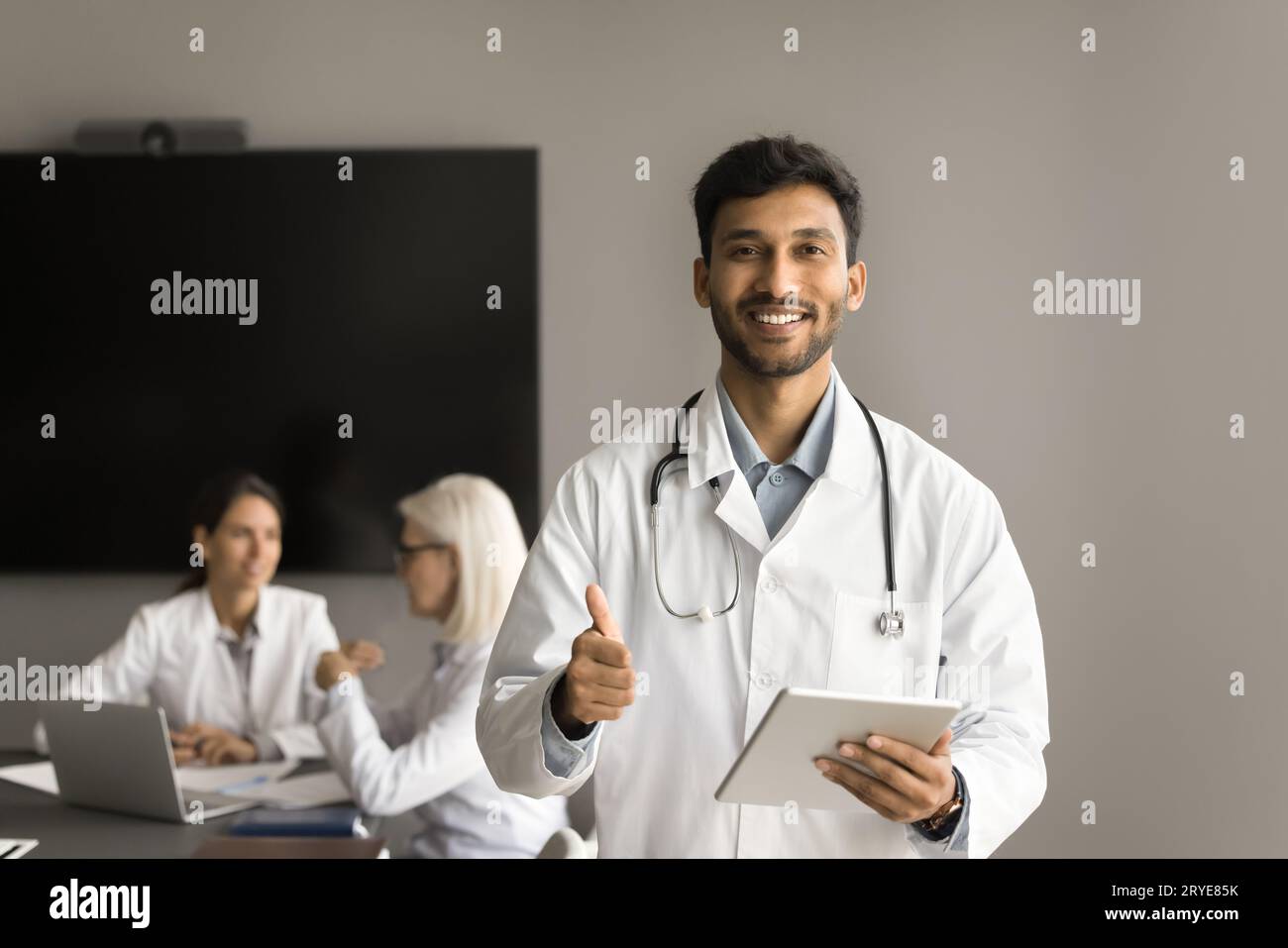 Happy young Indian doctor in white coat showing like hand Stock Photo ...