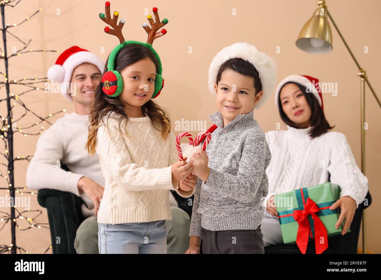 Little children with candy canes and their parents at home on Christmas ...