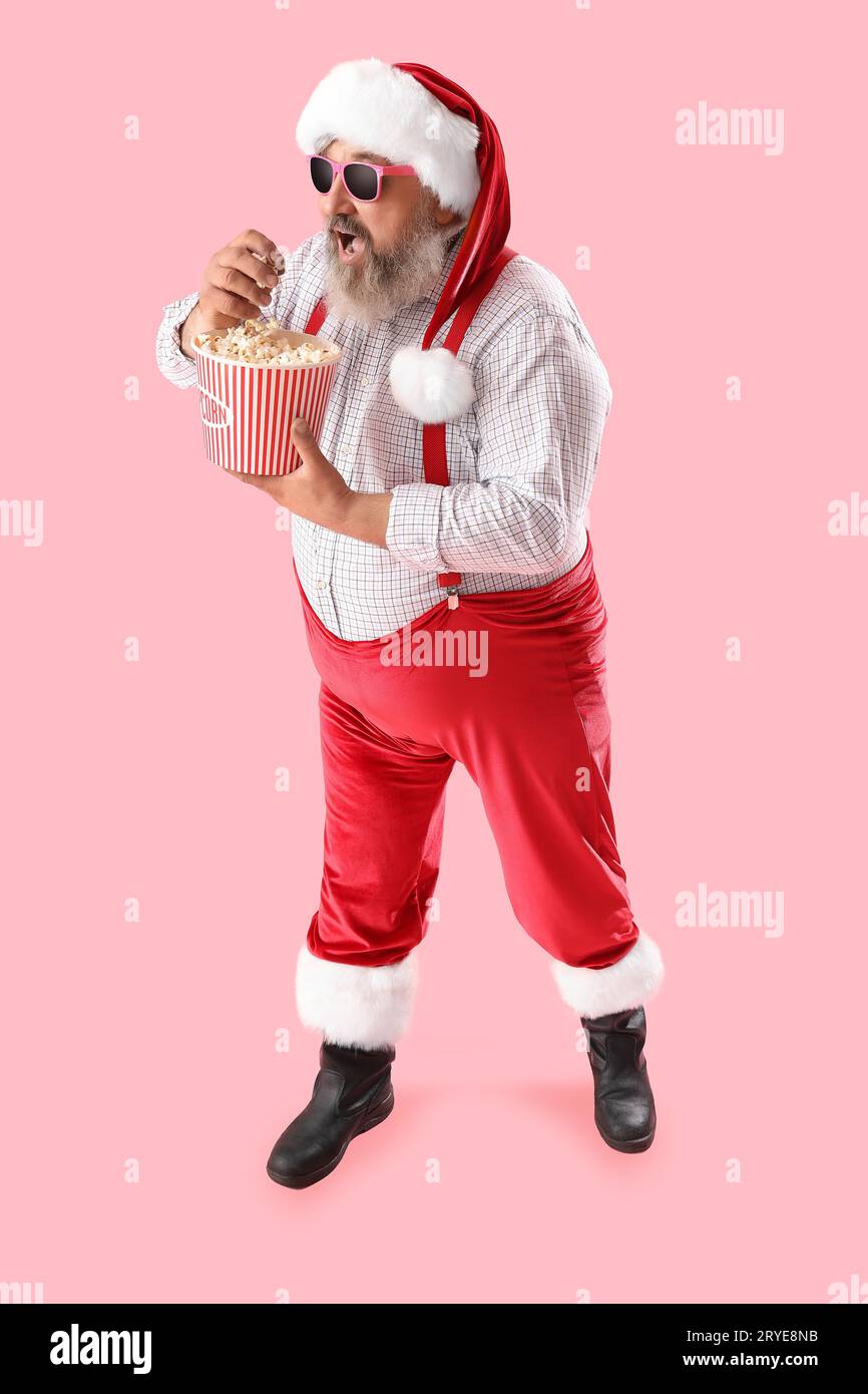 Santa Claus in sunglasses eating popcorn on pink background Stock Photo ...