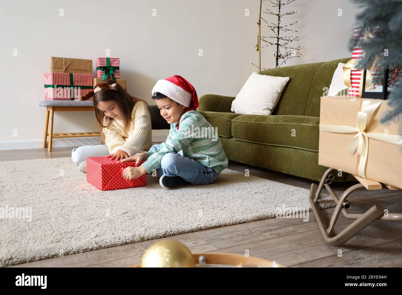 Cute little children unwrapping Christmas gift at home Stock Photo - Alamy